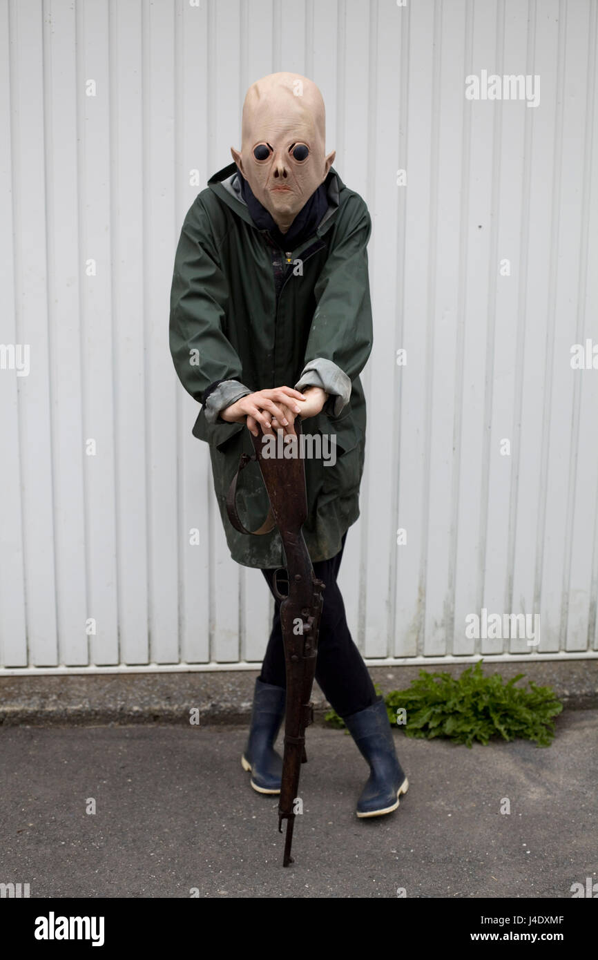 Colour photography. Woman wearing an alien mask hunting with shotgun in ...