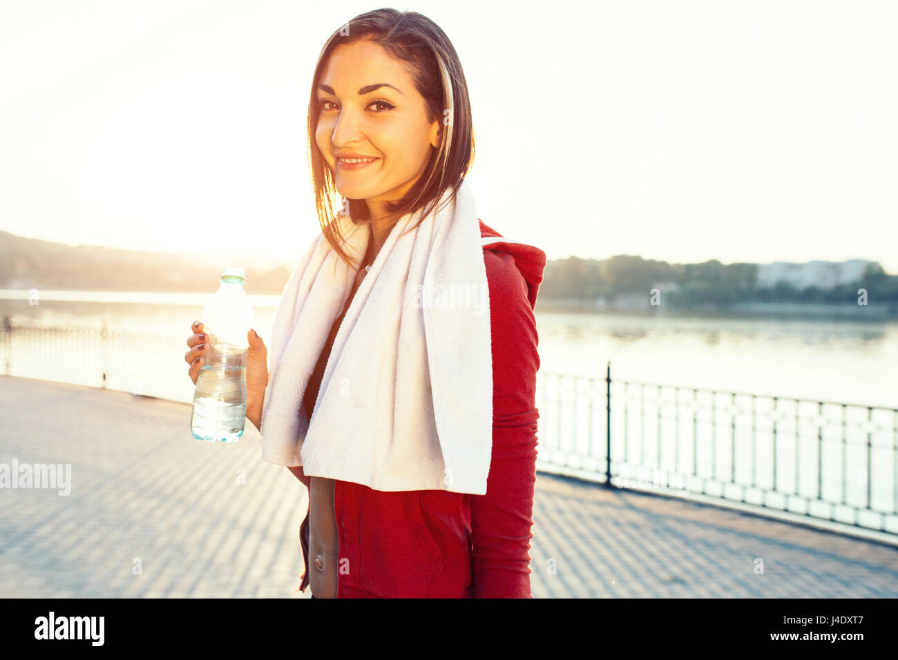 Smiling jogger woman by the lake at sunset. Sport and lifestyle concept ...