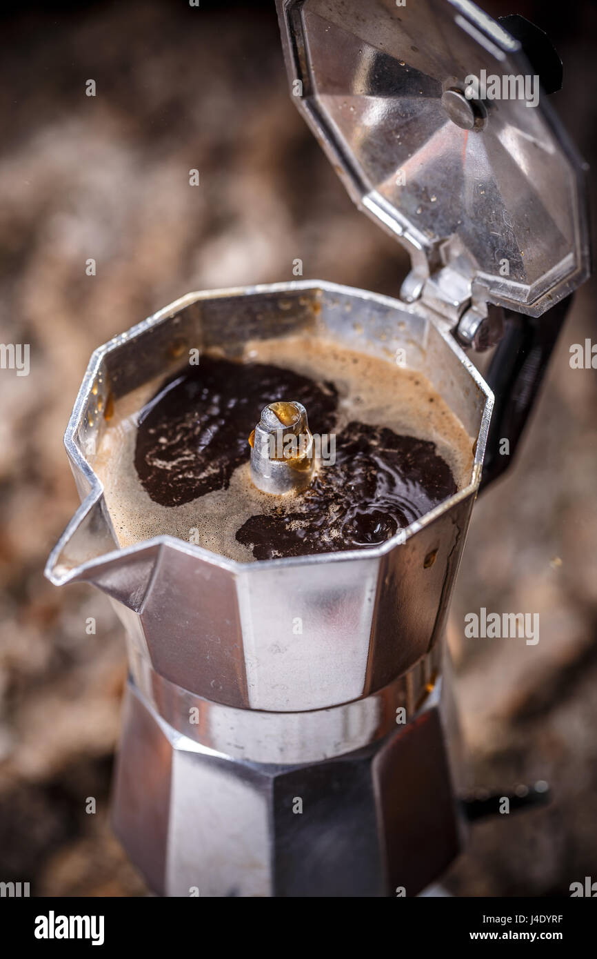 Italian traditional coffee maker with hot coffee flowing out from the ...