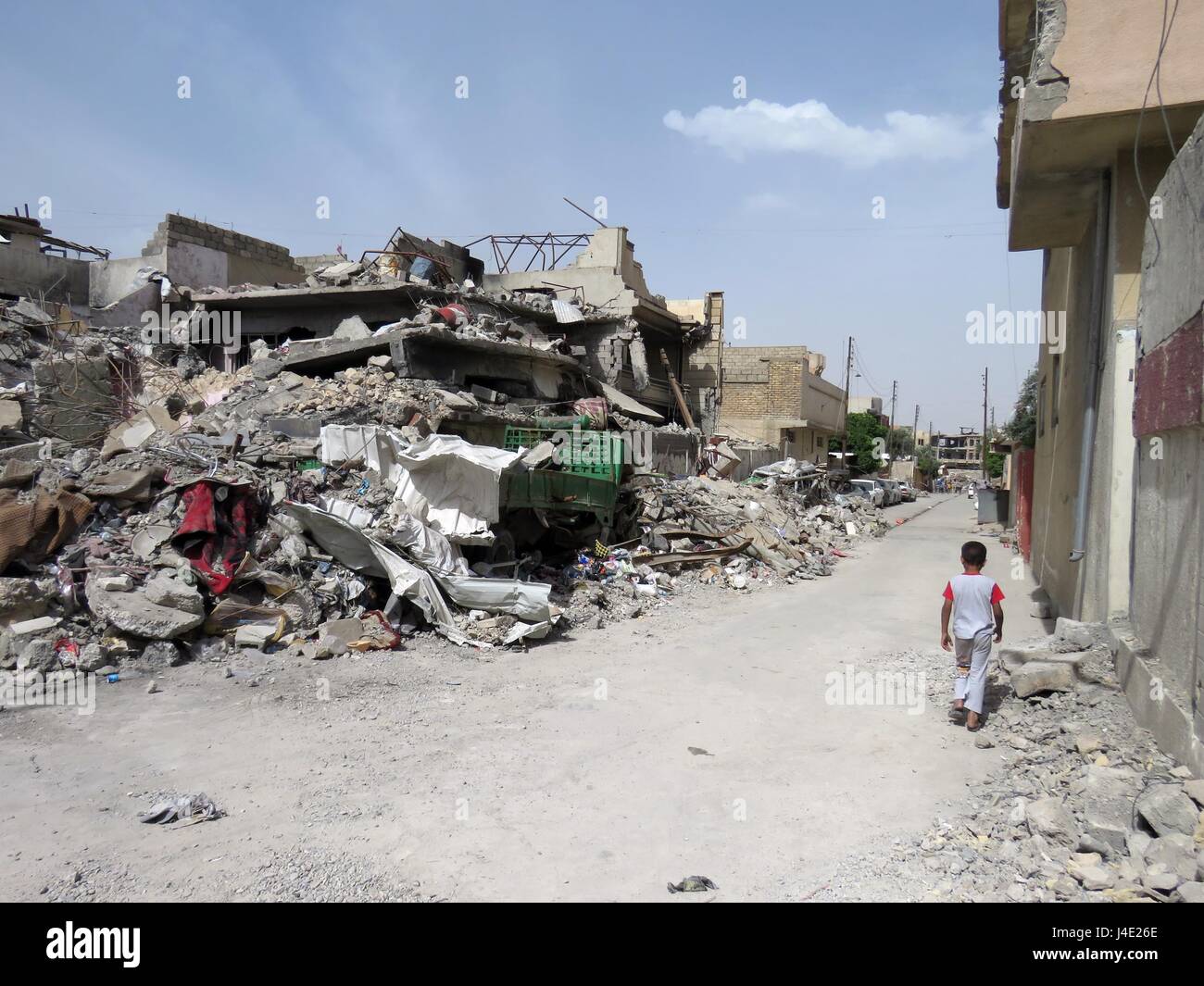 Mosul, Iraq. 11th May, 2017. A boy walks past damaged buildings in New ...