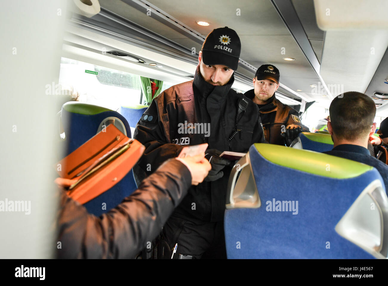 Police officers control a travelers on a bus at a parking lot in ...