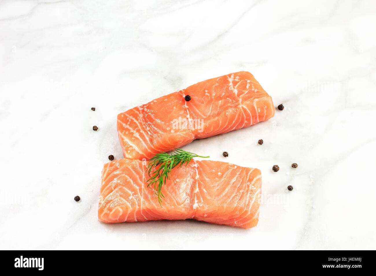 A photo of two slices of salmon on a white marble table with a place ...