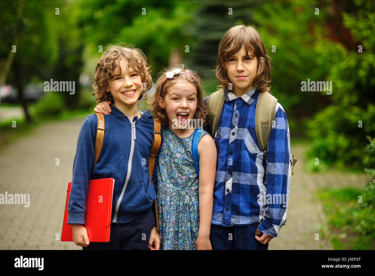 Three little school students, two boys and the girl, stand in an ...
