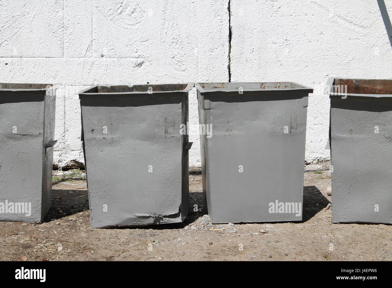 dumpsters standing in front of a white brick wall Stock Photo - Alamy