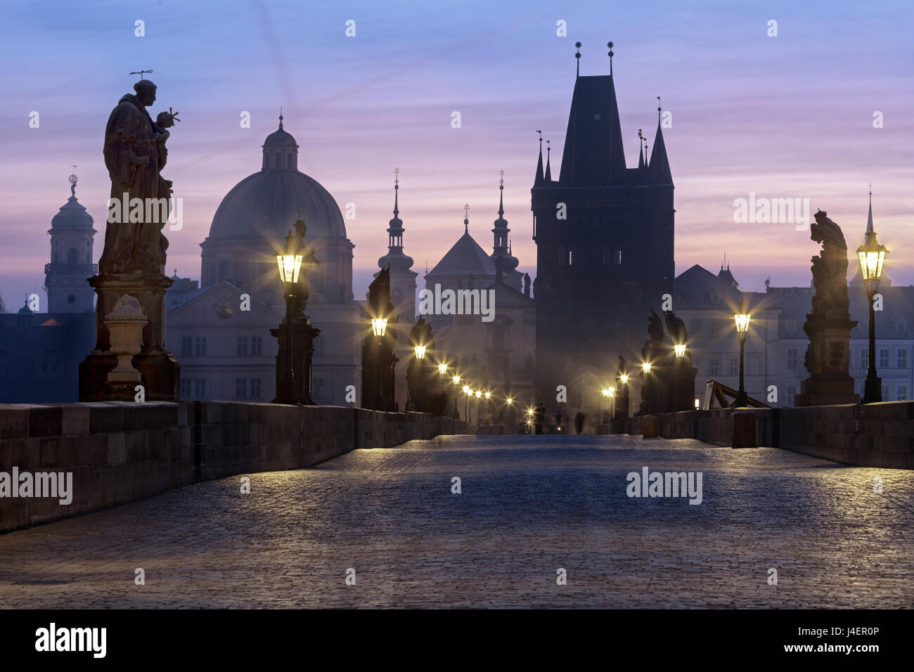 Street lanterns and old statues frame the historical buildings on Charles Bridge at dawn, UNESCO ...