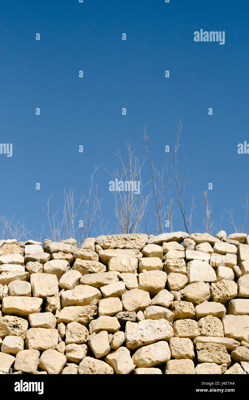 Abstract shot of sticks and grass in dry weather and rubble wall ...