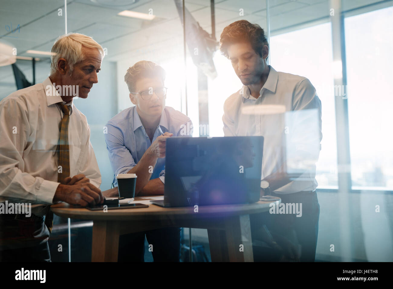 Businessmen standing around a table hi-res stock photography and images ...
