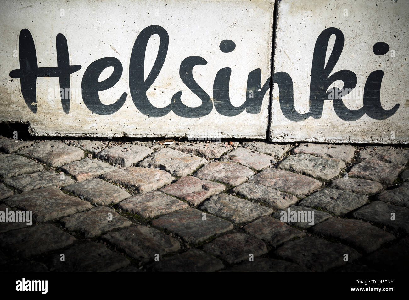 Helsinki sign on kerb by typical cobbled paving in the Finnish capital ...