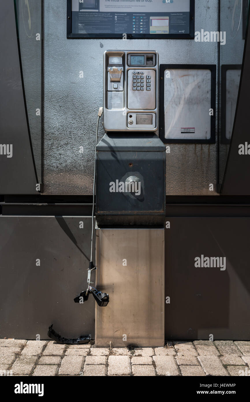 A vandalised phone booth with its handset smashed and hanging by its ...