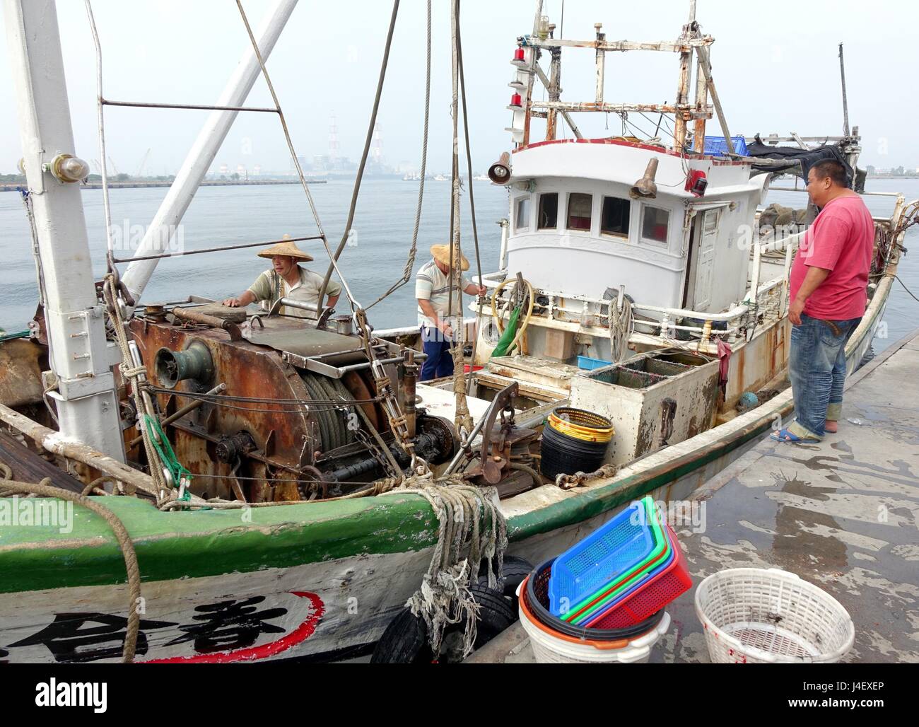KAOHSIUNG, TAIWAN -- MAY 3, 2014: Fishermen on board a boat docked at ...