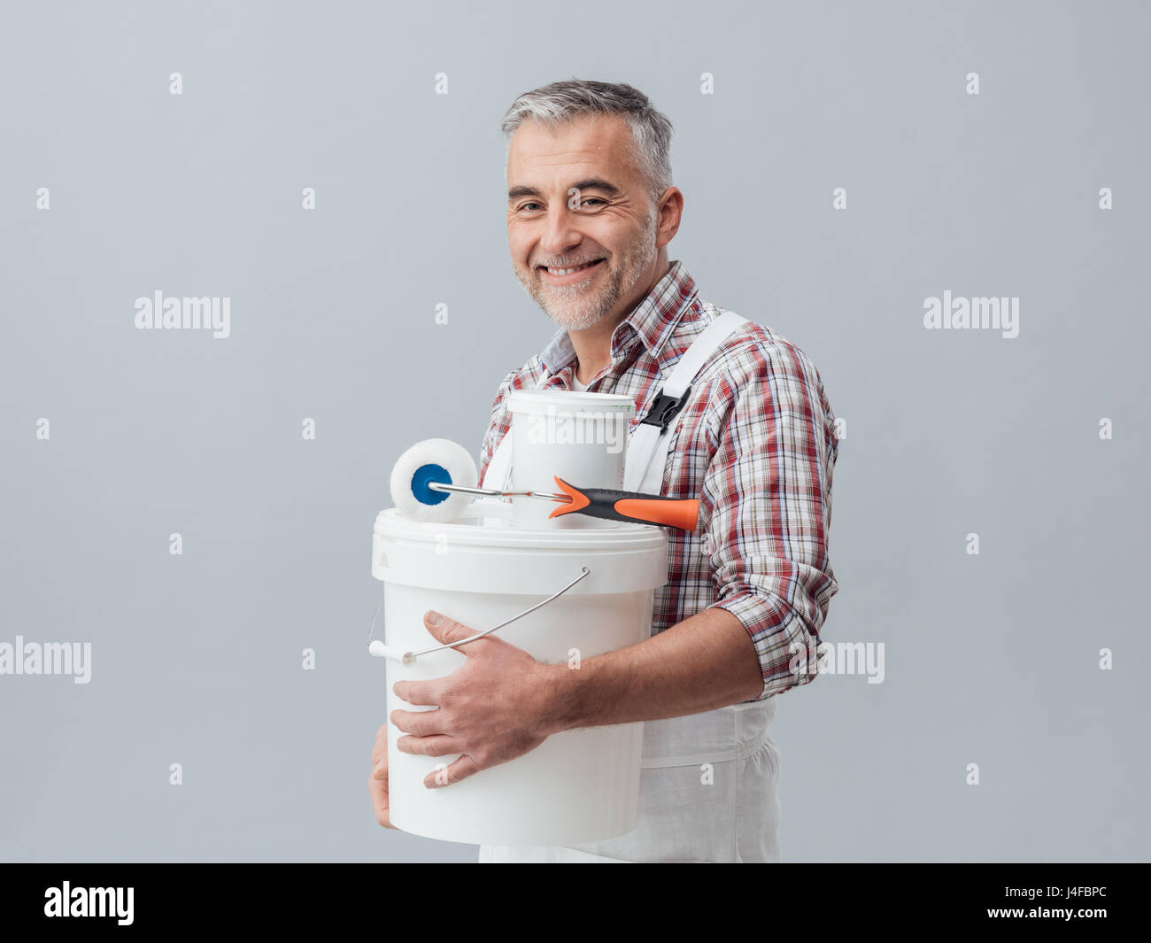 Smiling confident painter and decorator posing with a paint roller and ...