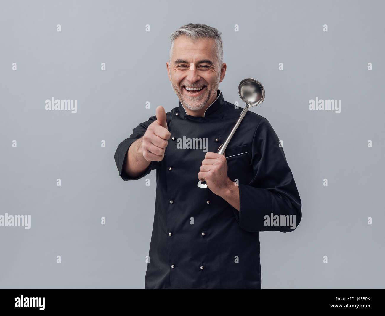Confident chef posing with a spoon ladle, he is smiling and giving a ...