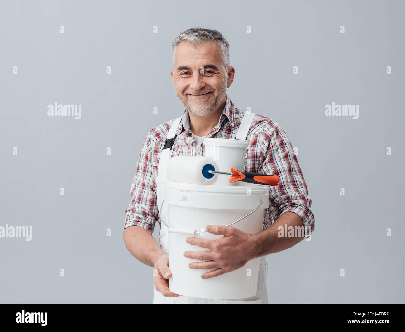 Smiling confident painter and decorator posing with a paint roller and ...