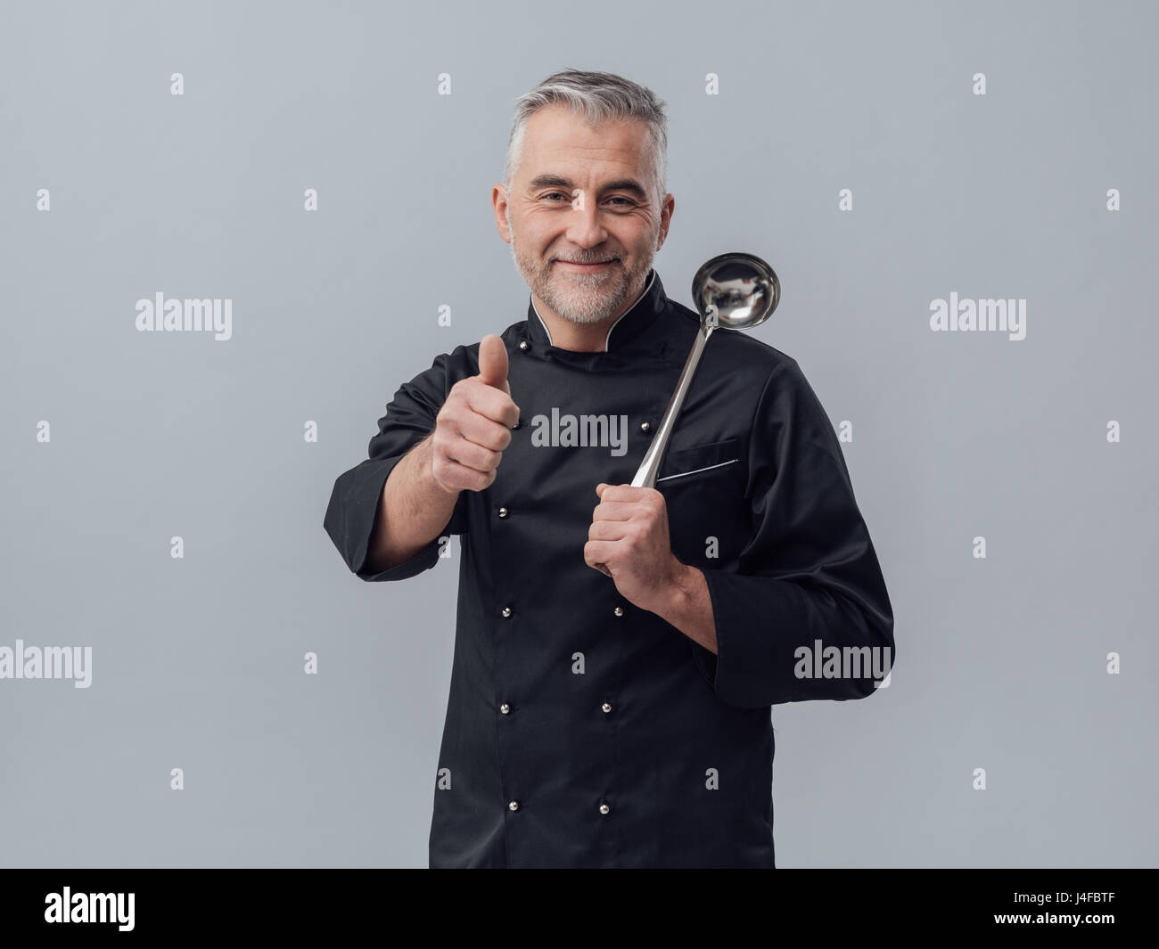 Confident chef posing with a spoon ladle, he is smiling and giving a ...