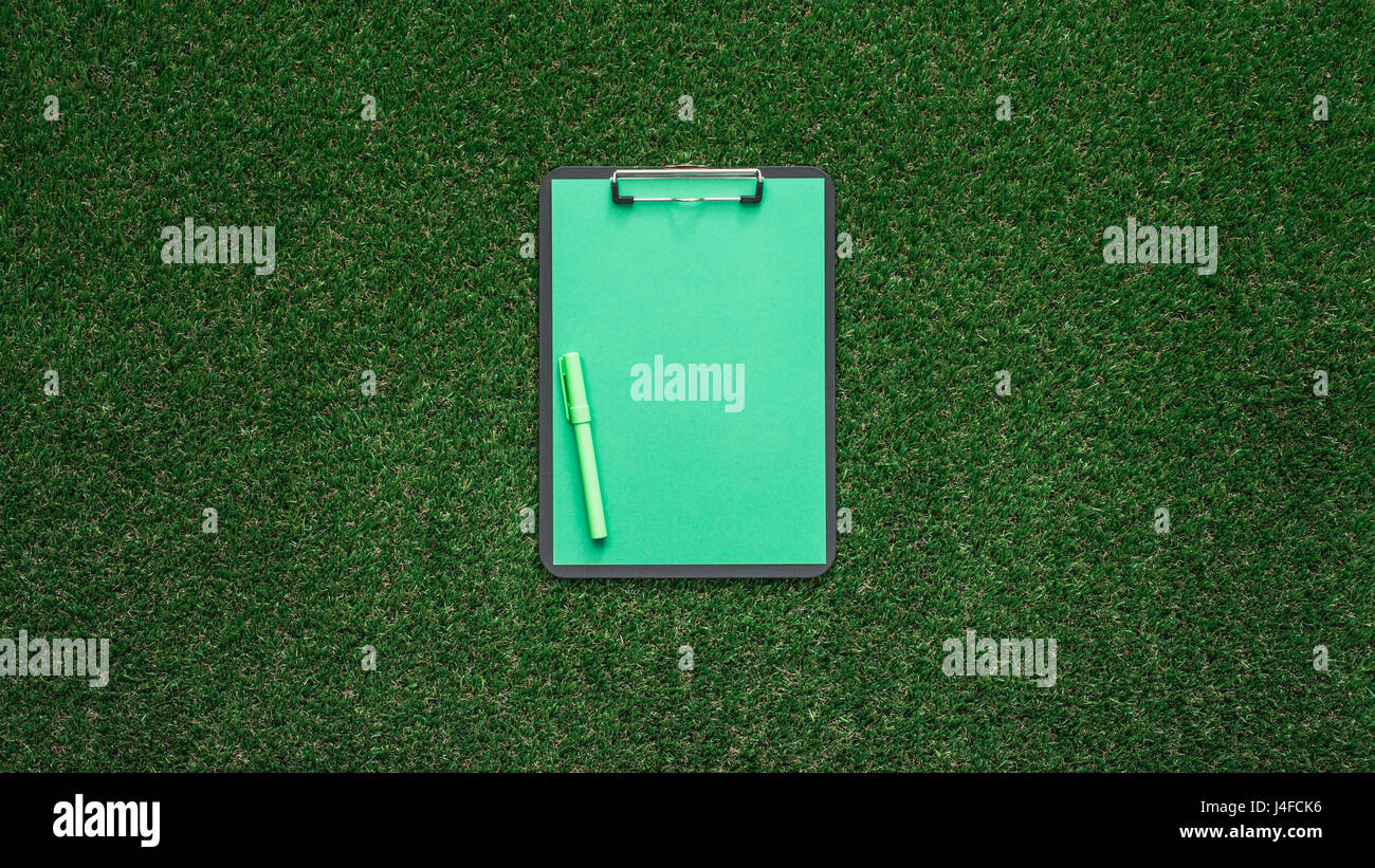 Green sheet and clipboard on lush grass, creativity and ecology concept ...