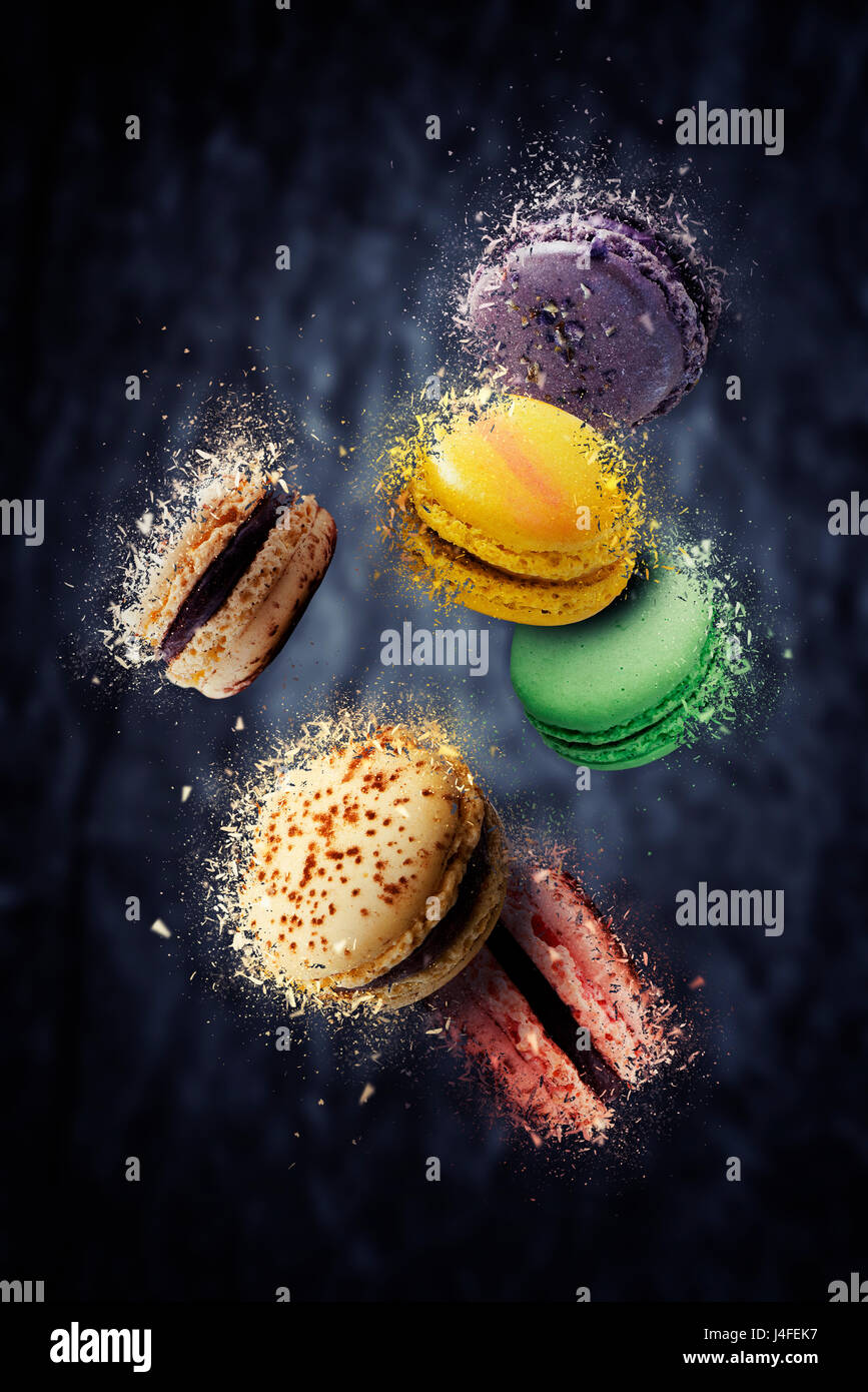 Assorted multi flavoured macaroons floating and exploding against black ...