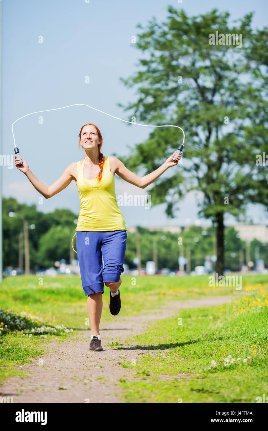 Young happy redhead woman jumping skipping rope Stock Photo - Alamy