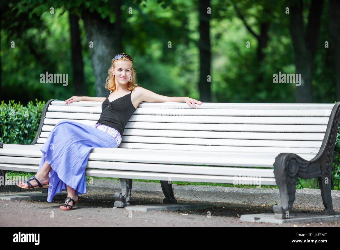 Young blond woman sitting alone on bench Stock Photo - Alamy