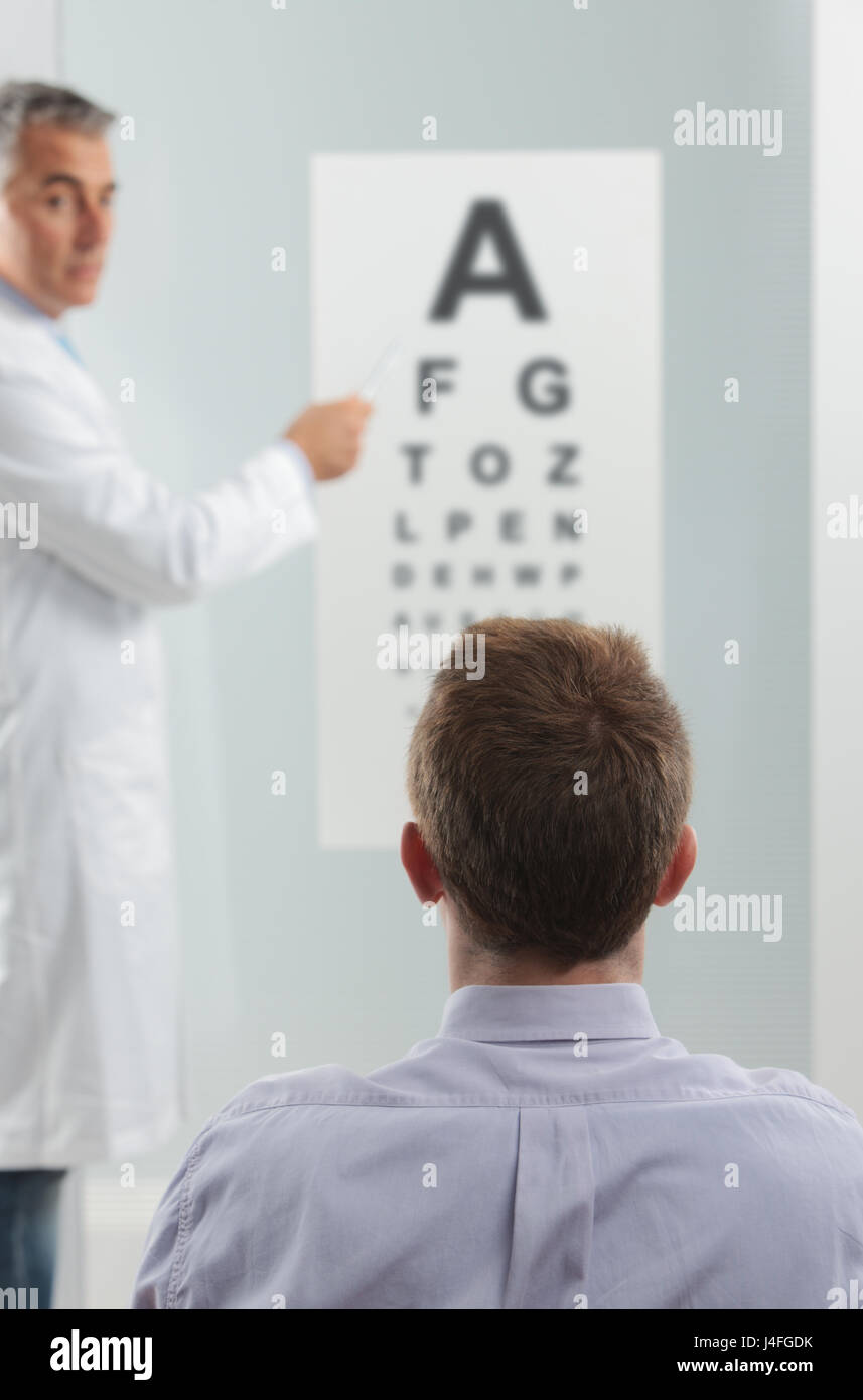 Optometrist and patient, doctor pointing at eye chart Stock Photo - Alamy