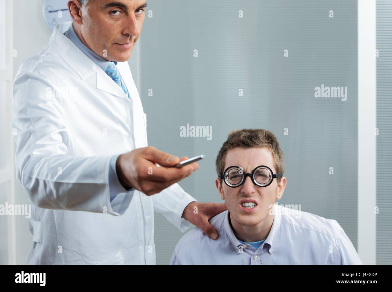 Optometrist pointing at eye chart, a nerd patient having difficulty ...