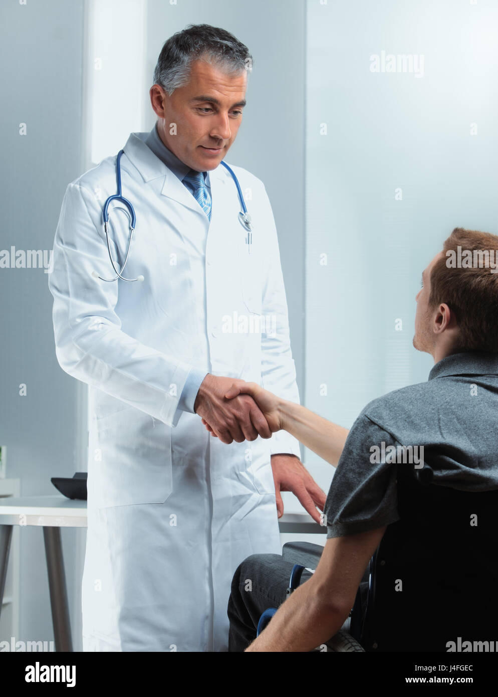 Mature doctor congratulates his disabled patient on a successful ...