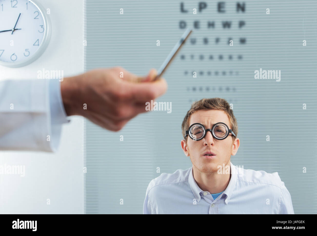 Optometrist pointing at eye chart, a nerd patient having difficulty ...