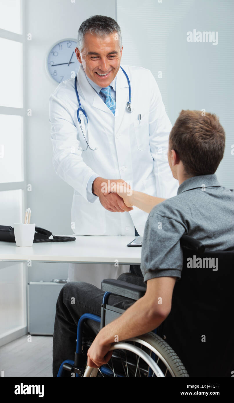 Mature doctor congratulates his disabled patient on a successful ...