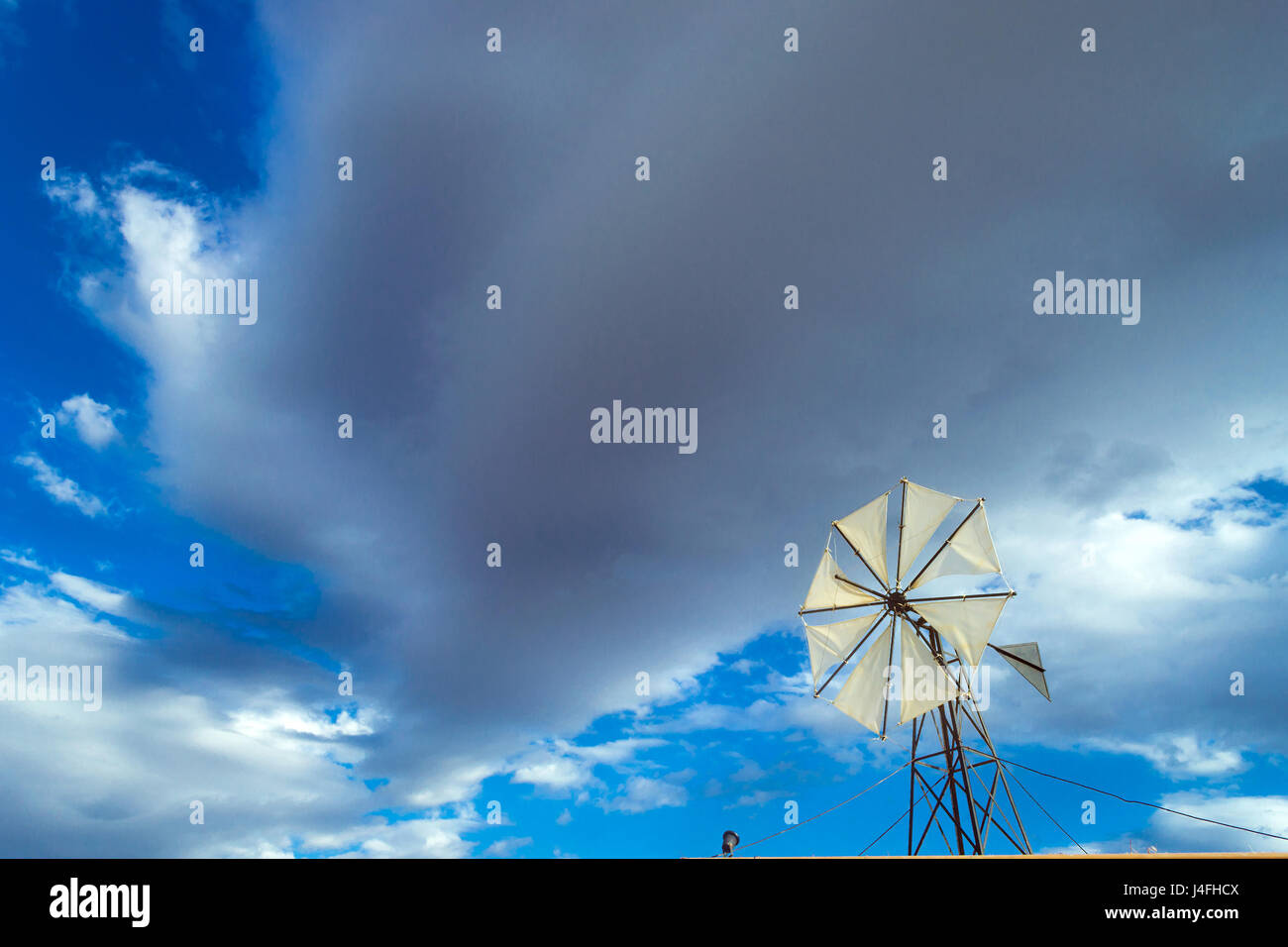 Decorative windmill with white propeller installed on thatched roof ...
