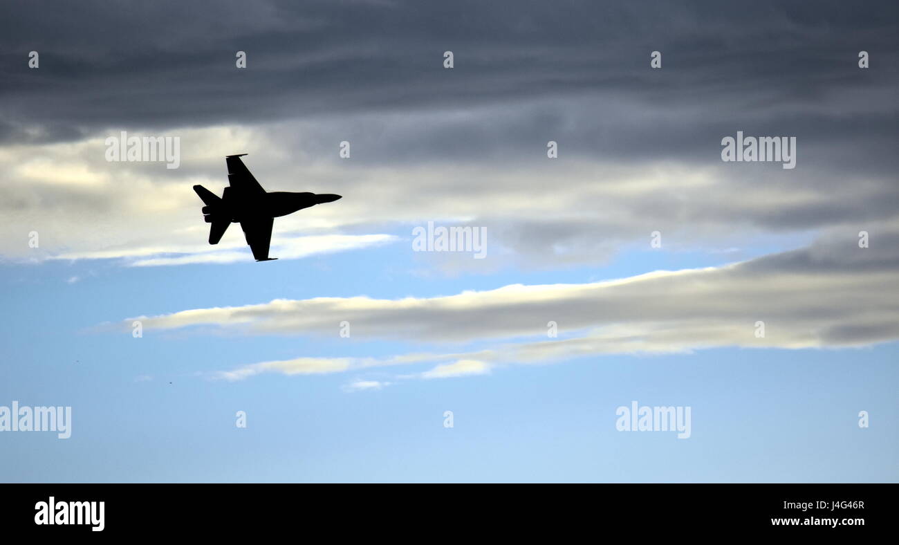 Silhouette of F18 Hornet fighter aircraft in flight. Clouds in the ...