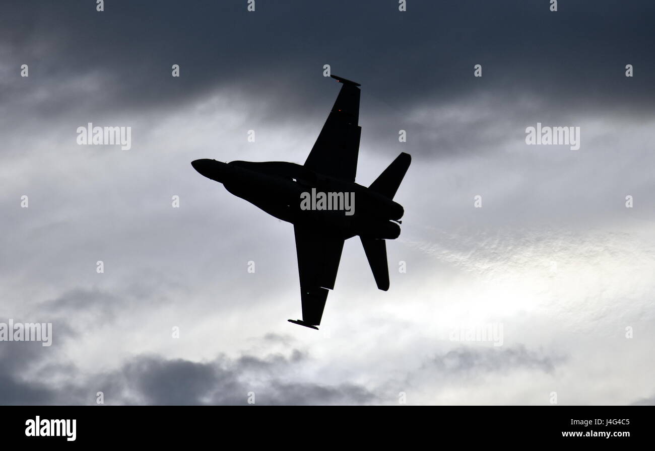 Silhouette of F18 Hornet fighter aircraft in flight. Clouds in the ...