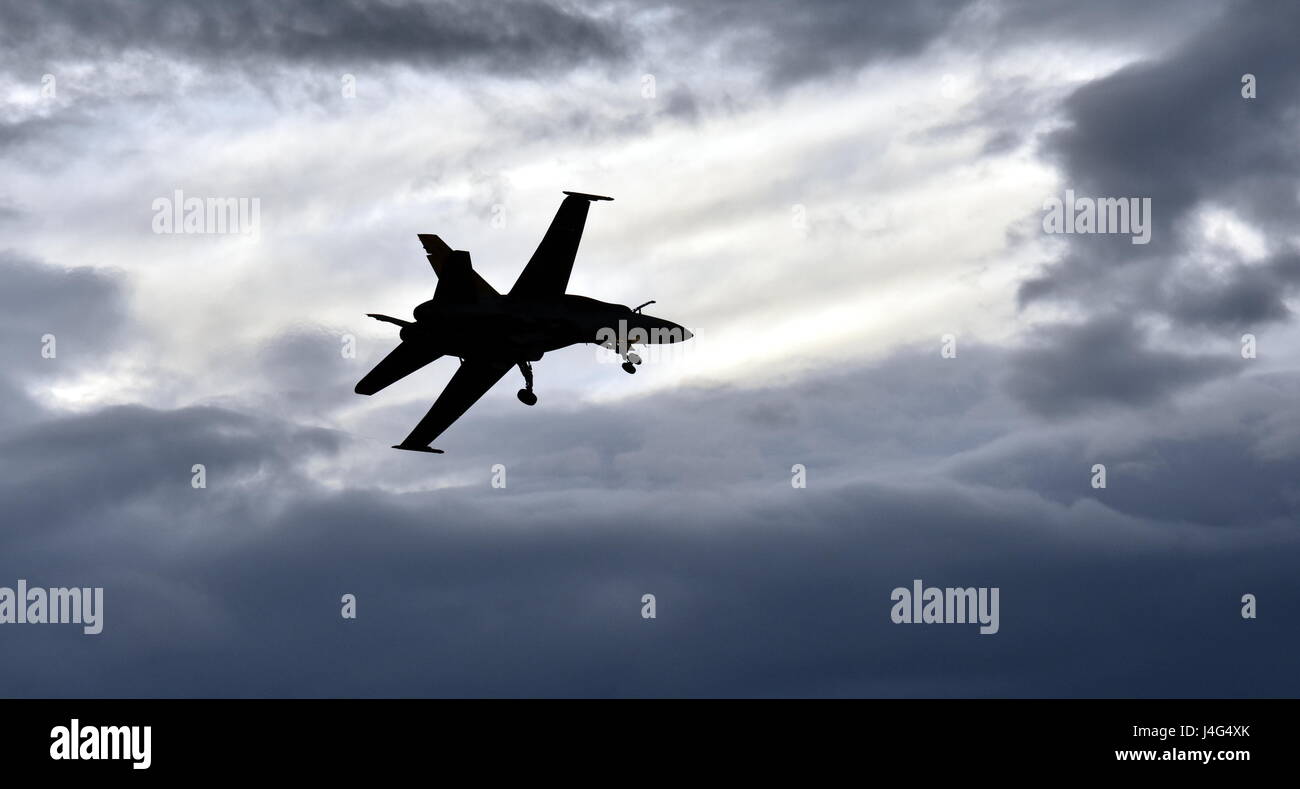 Silhouette of F18 Hornet fighter aircraft in flight. Clouds in the ...