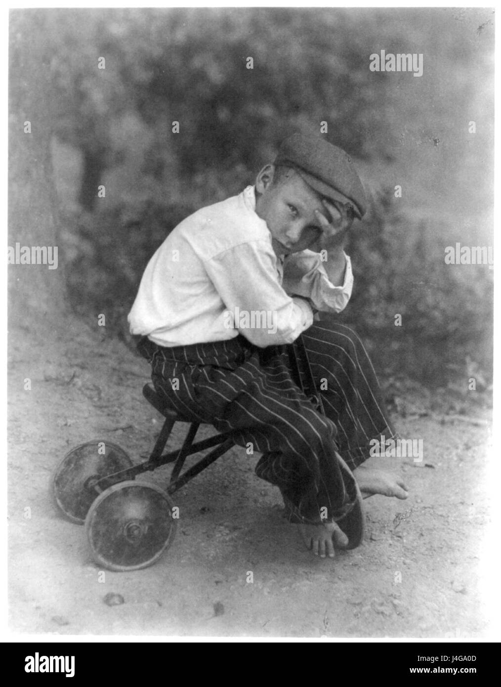 A photograph by Doris Ulmann showing a small boy riding a kiddie car ...