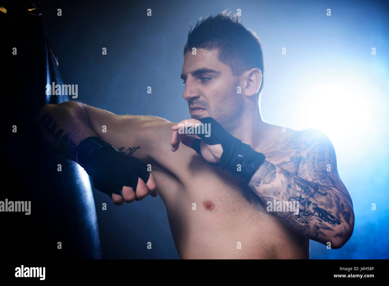 Motivated boxer exercising with punch bag Stock Photo - Alamy