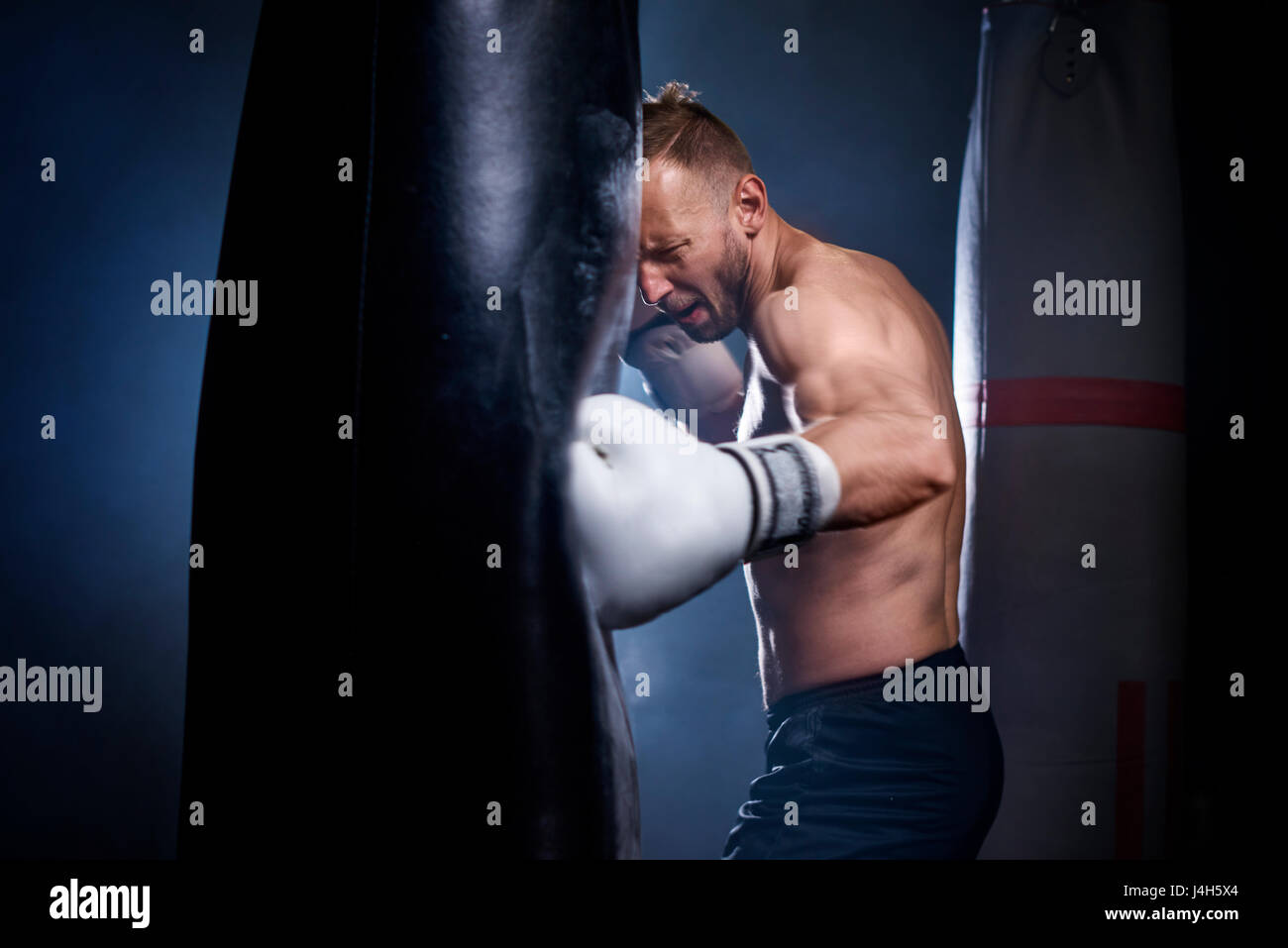 Male boxer using punch bag during training Stock Photo - Alamy