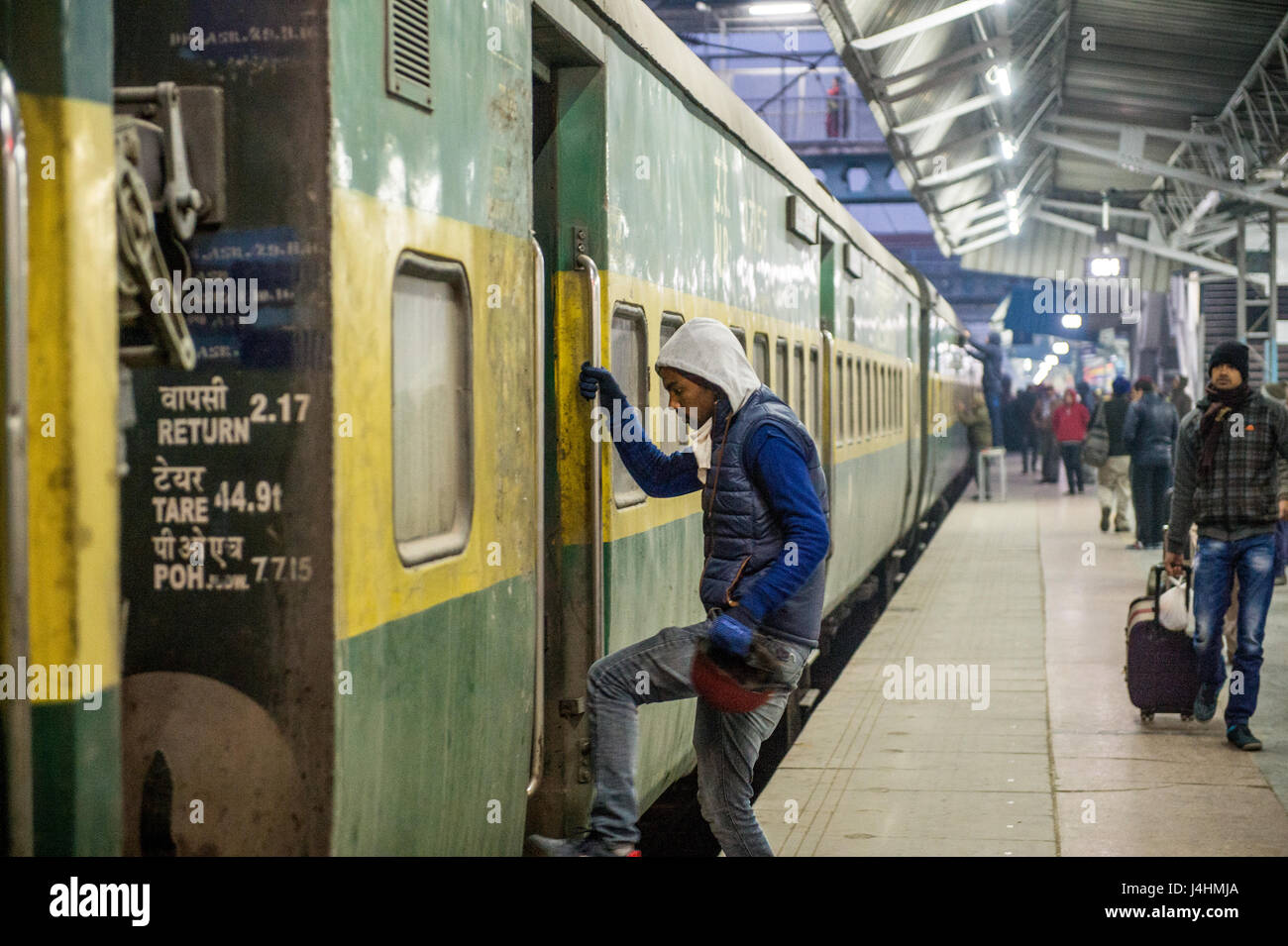 A young man steps onto a train car at the Ludhiana Junction railway ...