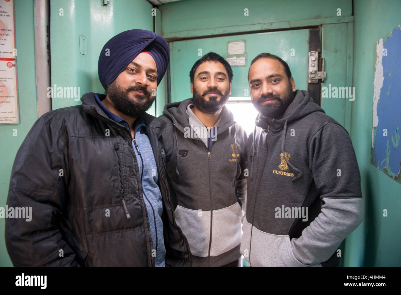 Indian men pose for a photograph while aboard a train in Ludhiana ...