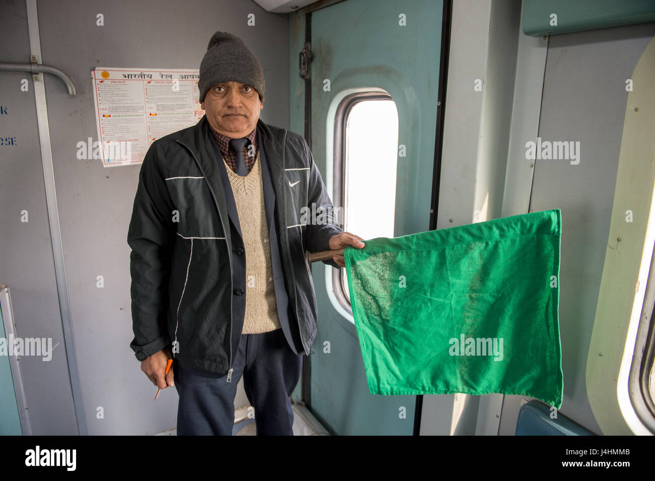 A man is holding a green flag aboard a train in Ludhiana, India Stock ...