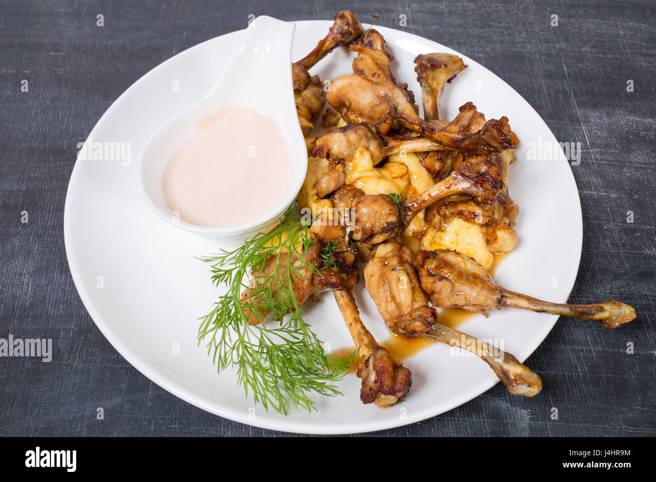 Chicken legs with melted cheese and delicious sauce. Plate located on a ...