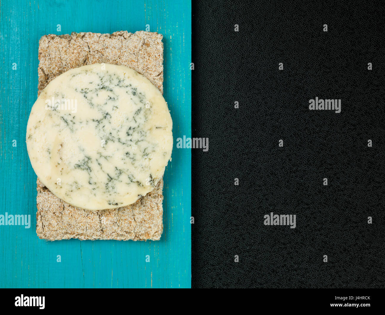 Blue Stilton Cheese on Thin Crisp Wholewheat Crackers Against a BLue ...