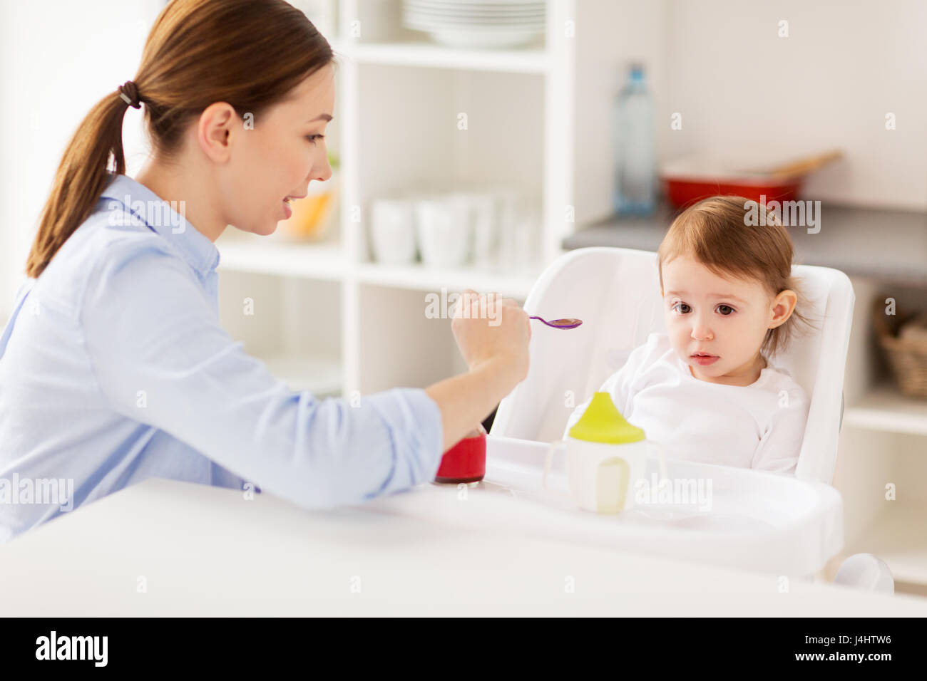 happy mother feeding baby with puree at home Stock Photo - Alamy