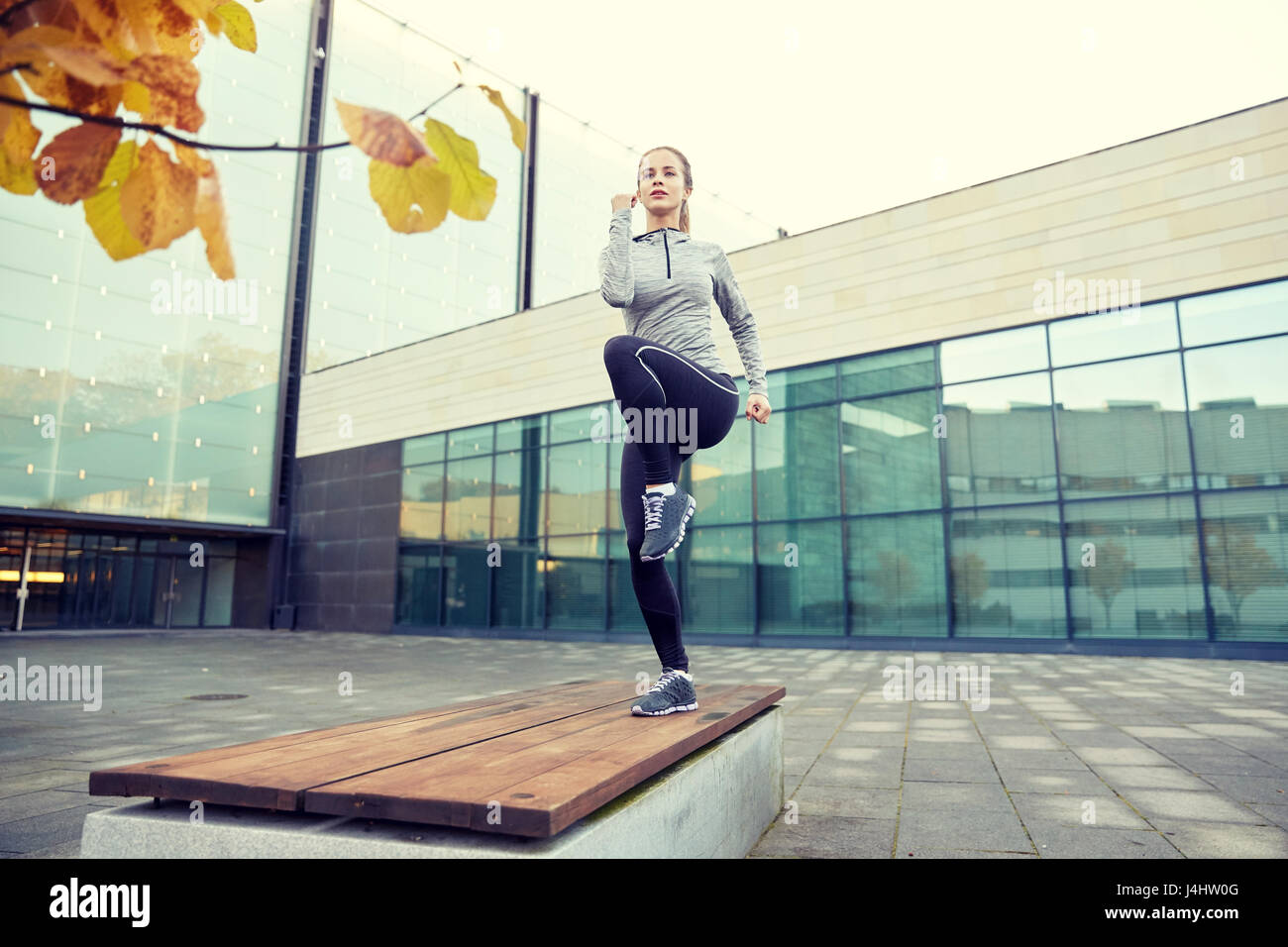 woman making step exercise on city street bench Stock Photo - Alamy