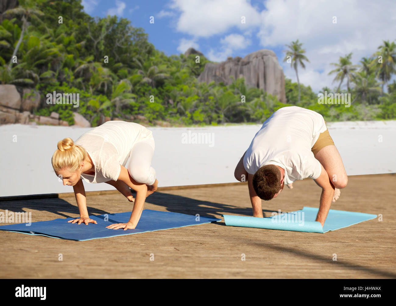 couple making yoga crow pose over tropical beach Stock Photo - Alamy