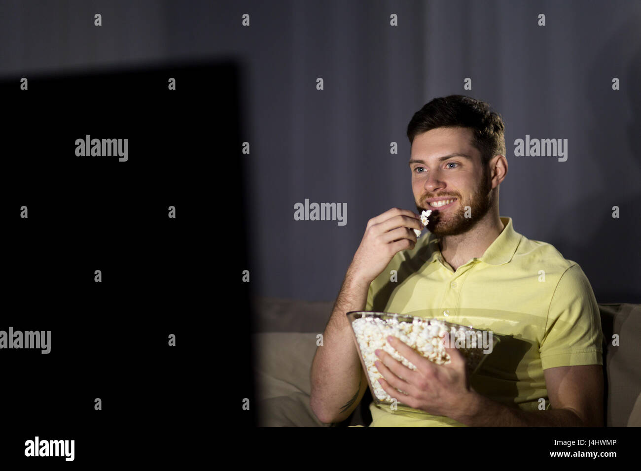 happy man with popcorn watching tv at night Stock Photo - Alamy