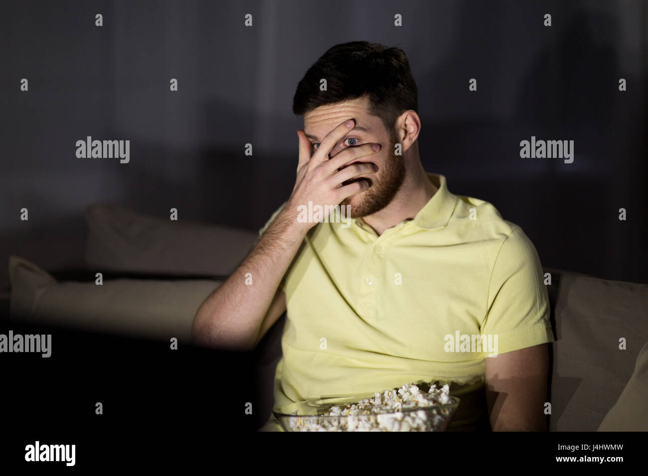 scared man watching tv and eating popcorn at night Stock Photo - Alamy