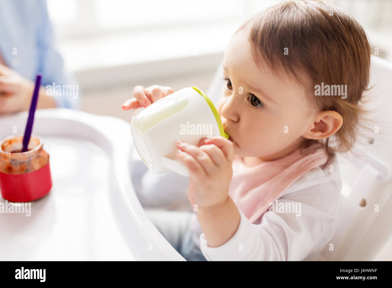 baby drinking from spout cup in highchair at home Stock Photo - Alamy