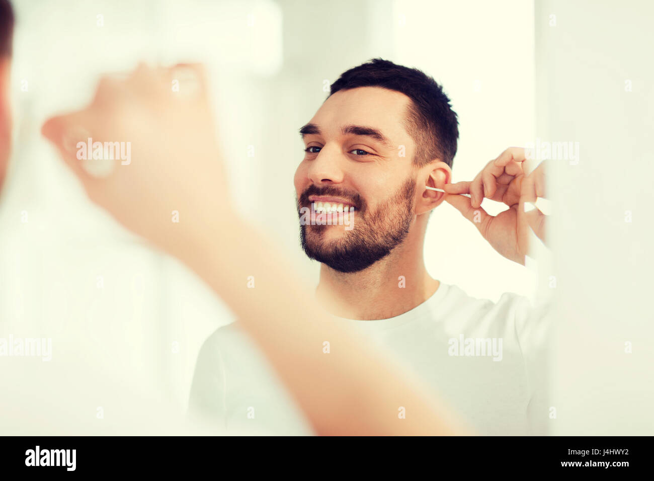 man cleaning ear with cotton swab at bathroom Stock Photo - Alamy
