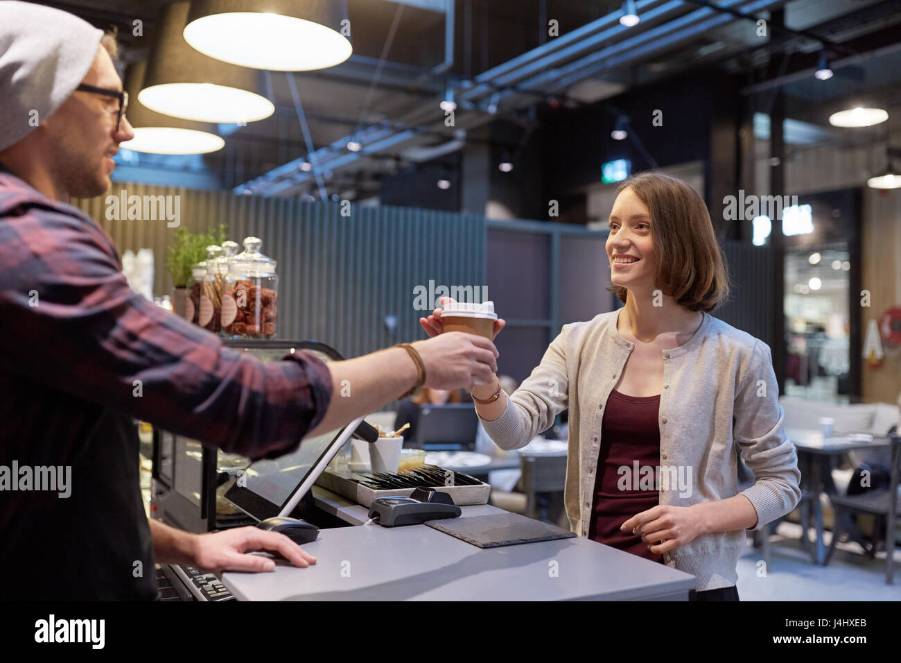 seller giving coffee cup to woman customer at cafe Stock Photo - Alamy