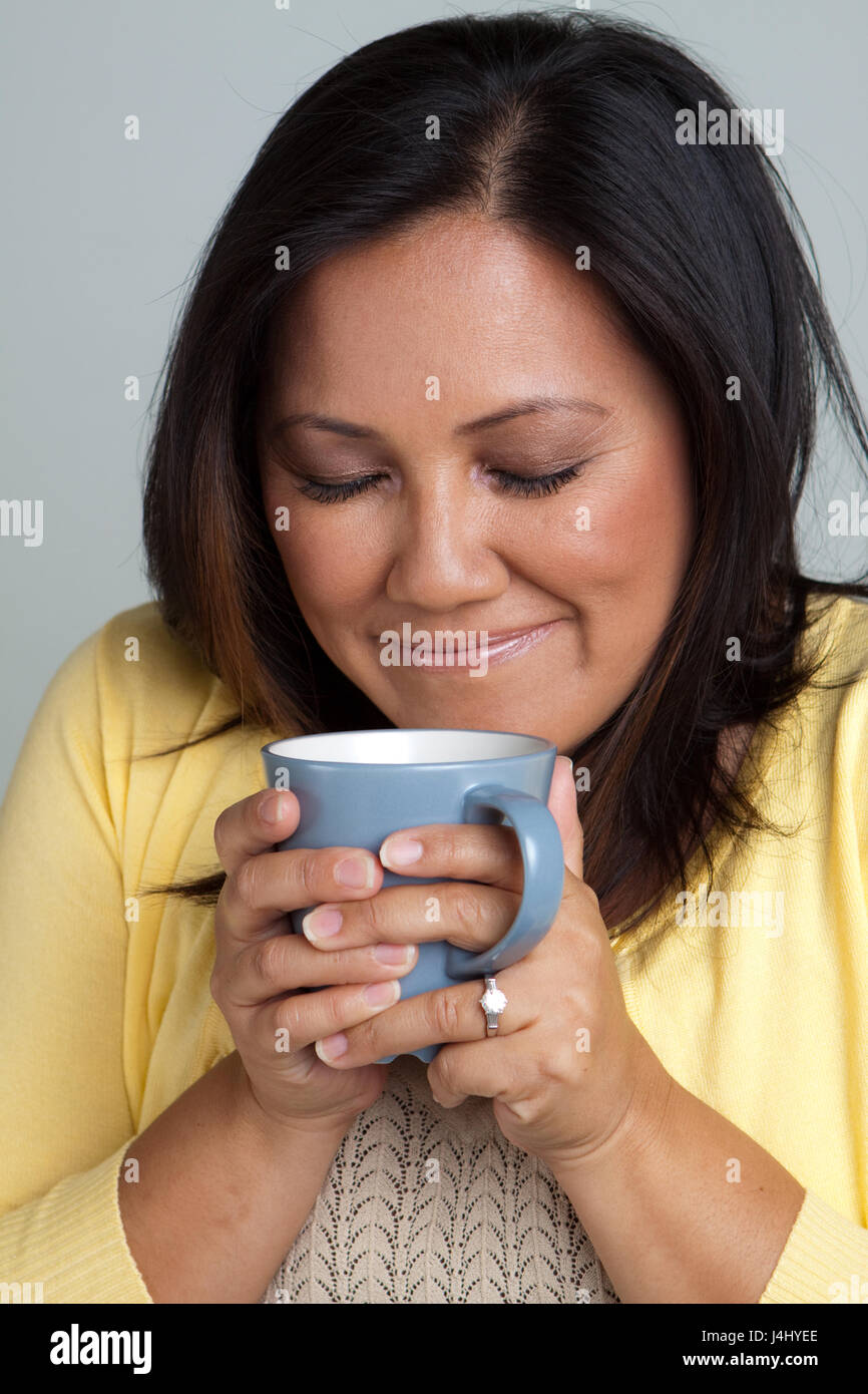 Happy Asian woman enjoying a cup of tea Stock Photo - Alamy