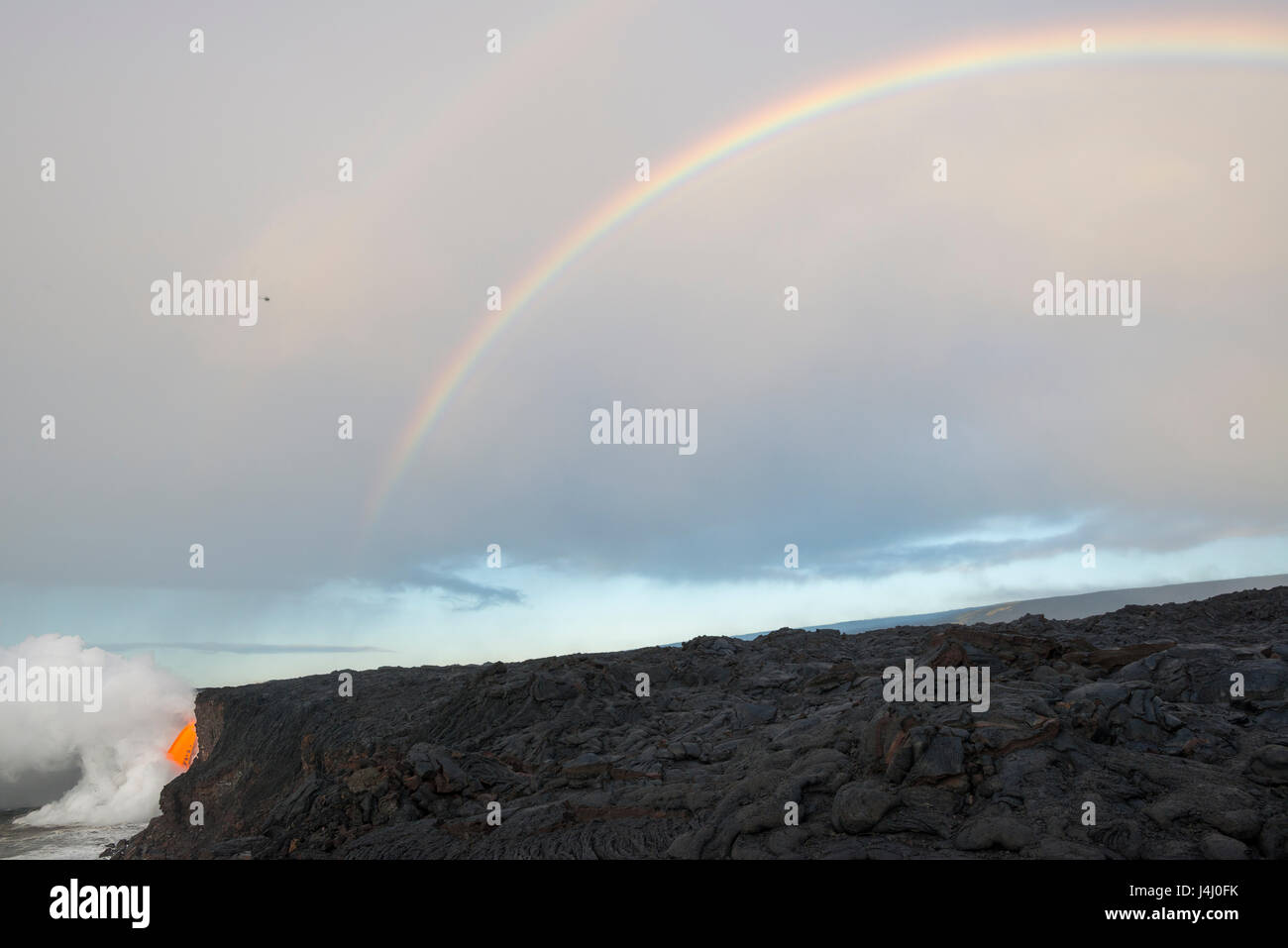 a rainbow touches down where hot lava from the 61G flow from Kilauea ...