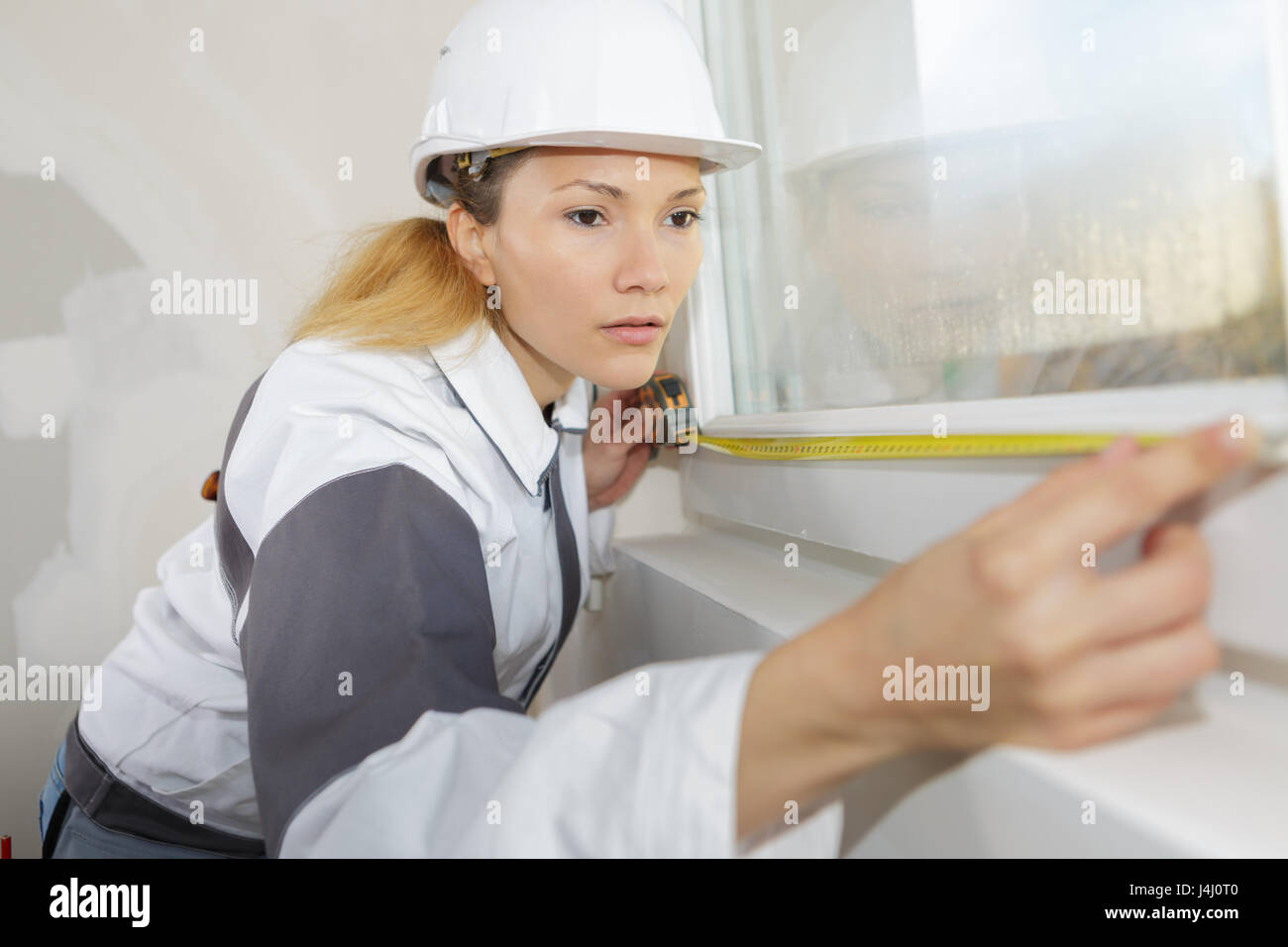 female builder measuring a window Stock Photo - Alamy